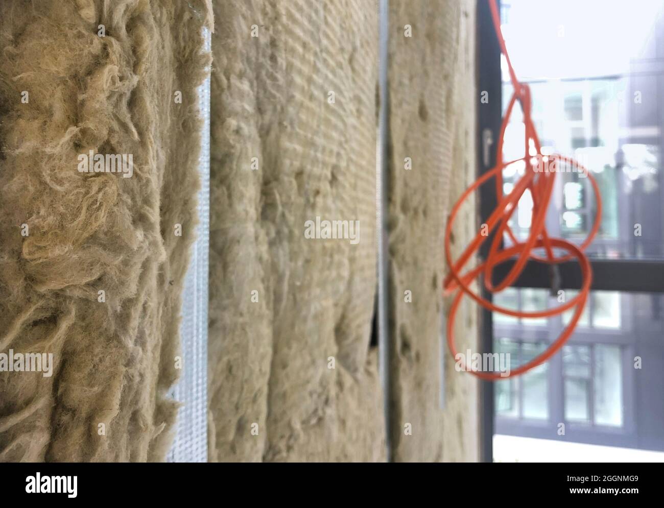 Open insulation and a cable hanging from a wall at a construction site ...