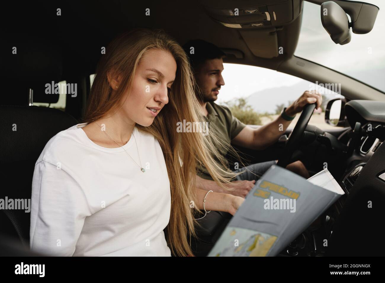 Young loving couple on a road trip using map inside a car Stock Photo ...