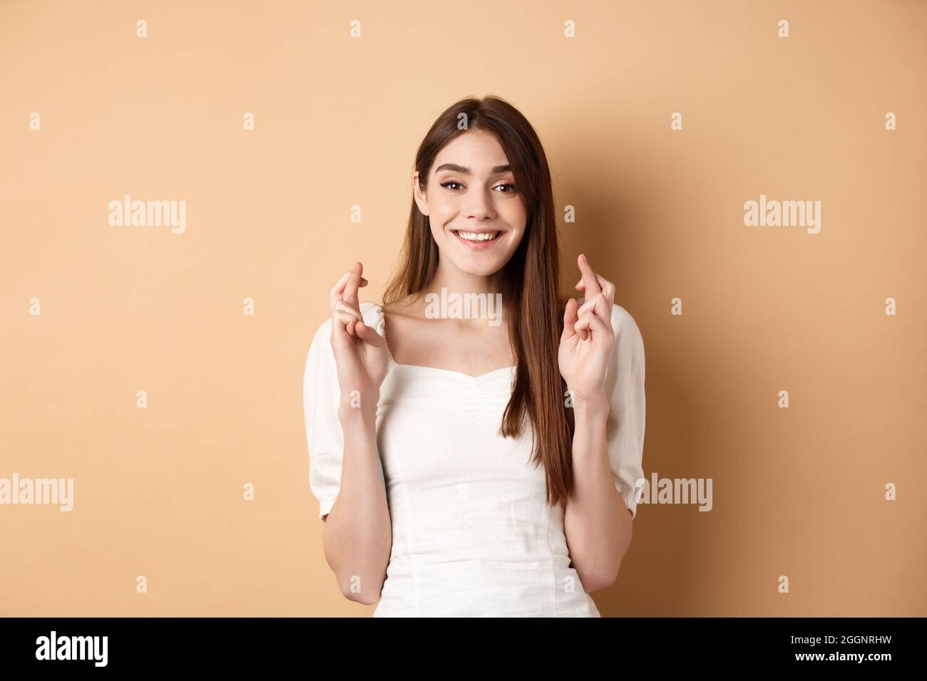 Positive girl making wish with fingers crossed, smiling and feeling ...