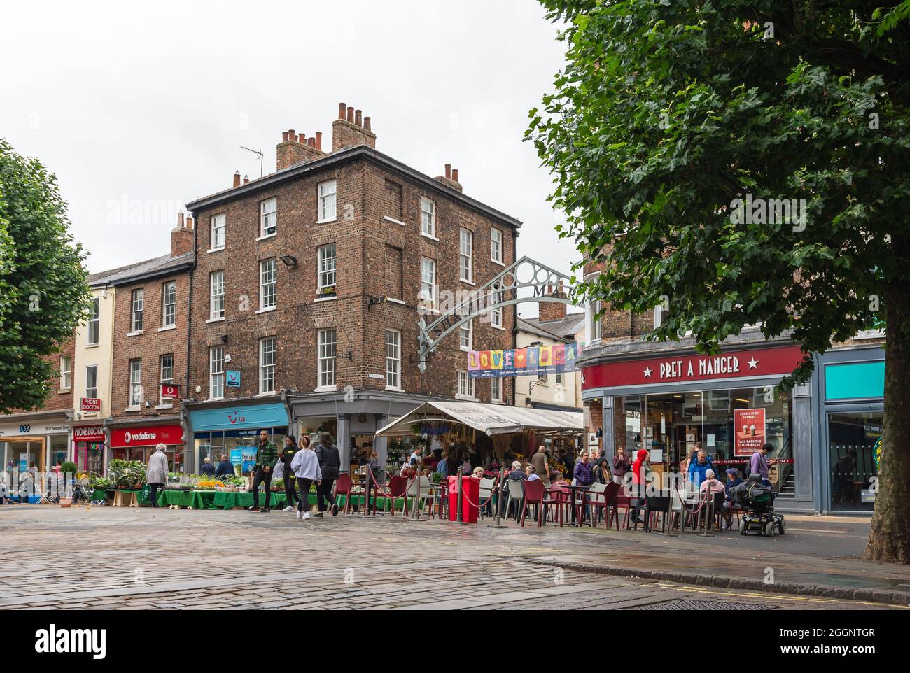 A pedestrian shopping street with people sitting outside at a cafe ...
