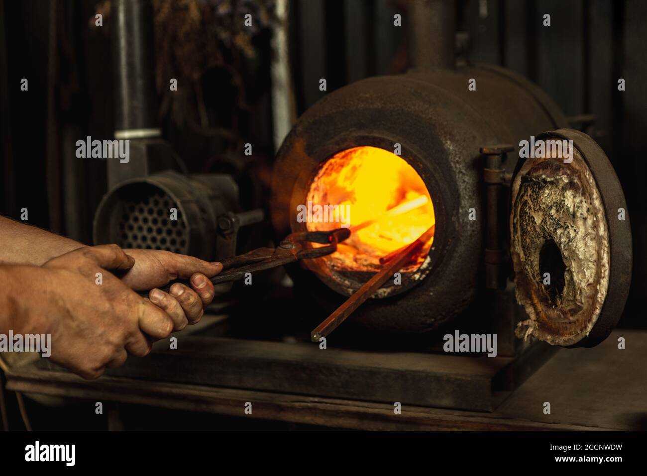 Close-up working powerful hands of male blacksmith making red hot metal ...