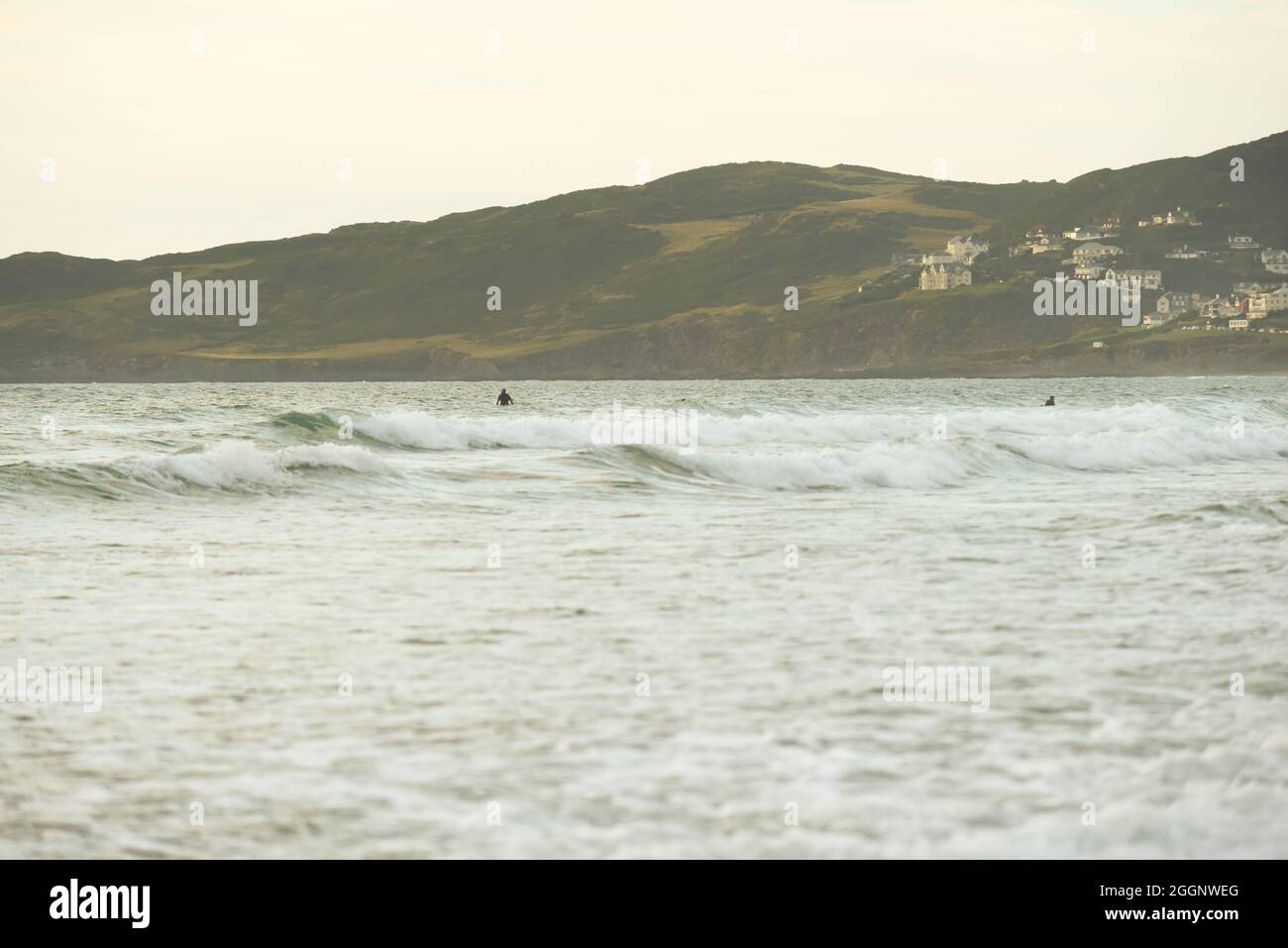 View from the shore at the beach with people surfing ocean waves in the ...