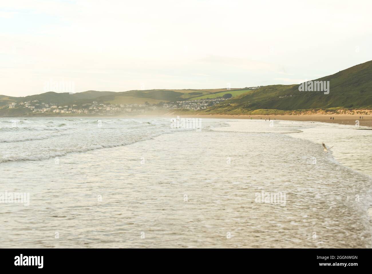 View from the shore at the beach with people surfing ocean waves in the ...