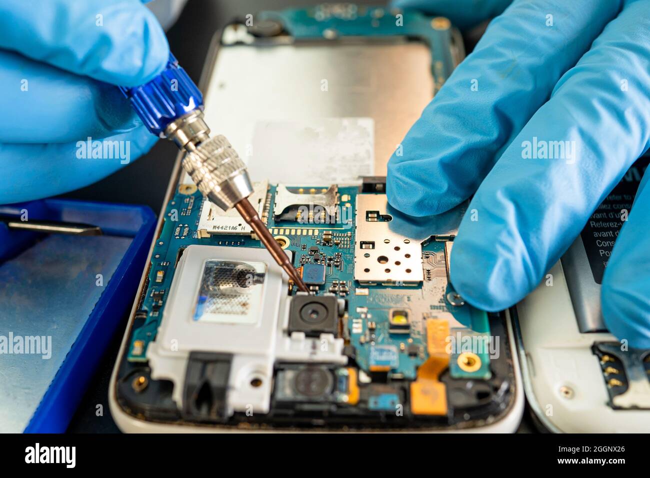 Technician repairing inside of mobile phone by soldering iron ...