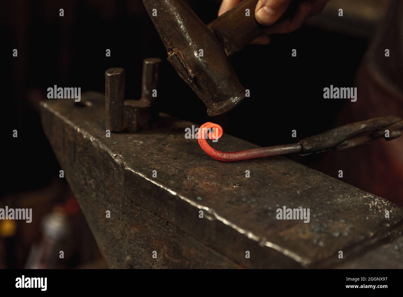 Close-up hands of male blacksmith forge an iron product in a blacksmith ...