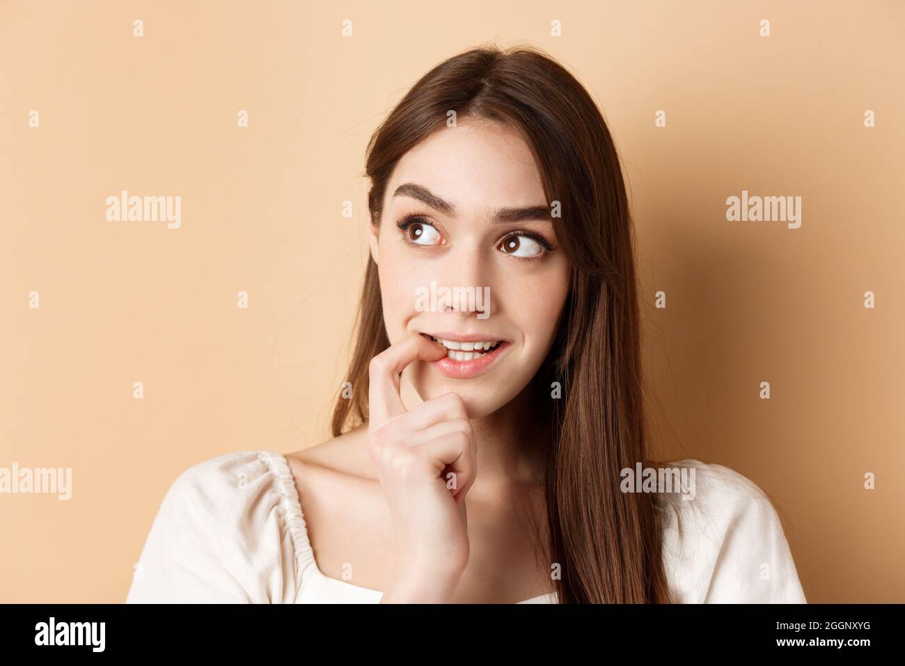 Close up of cute young woman thinking, biting fingernail and look ...