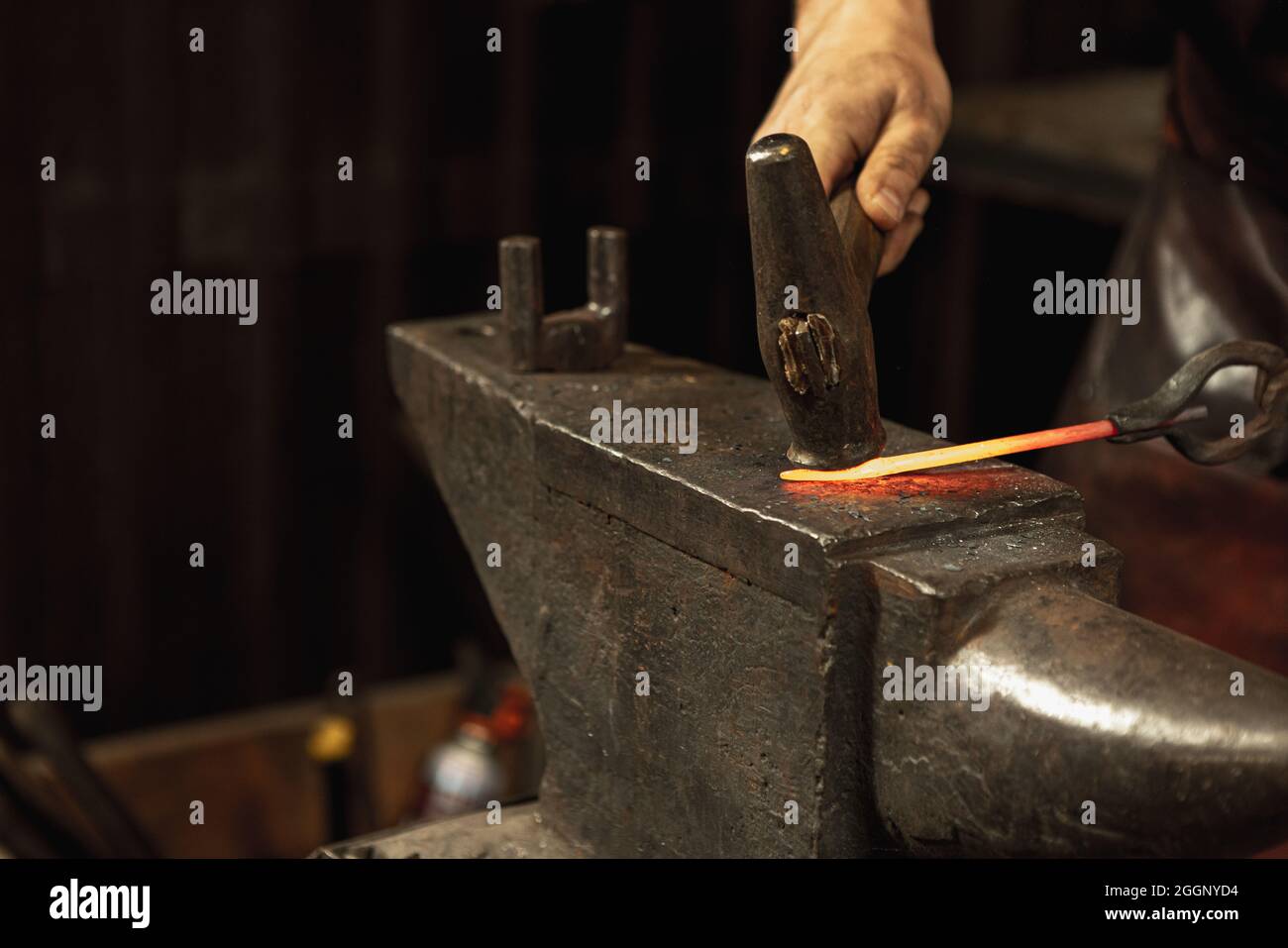 Close-up working powerful hands of male blacksmith forge an iron ...
