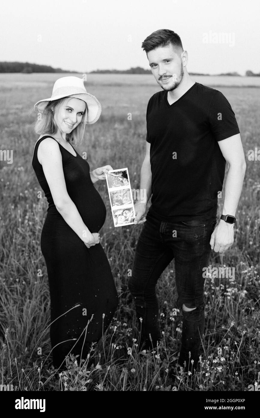 Young pregnant couple holds ultrasound image of their unborn child in ...