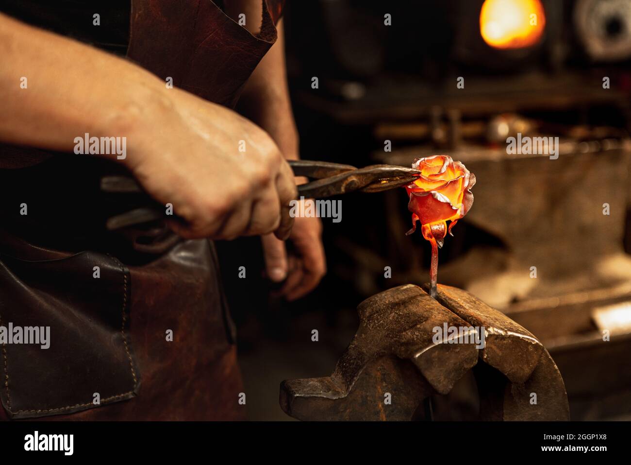 Beautiful rose. Blacksmith manually forging molten metal on anvil in ...