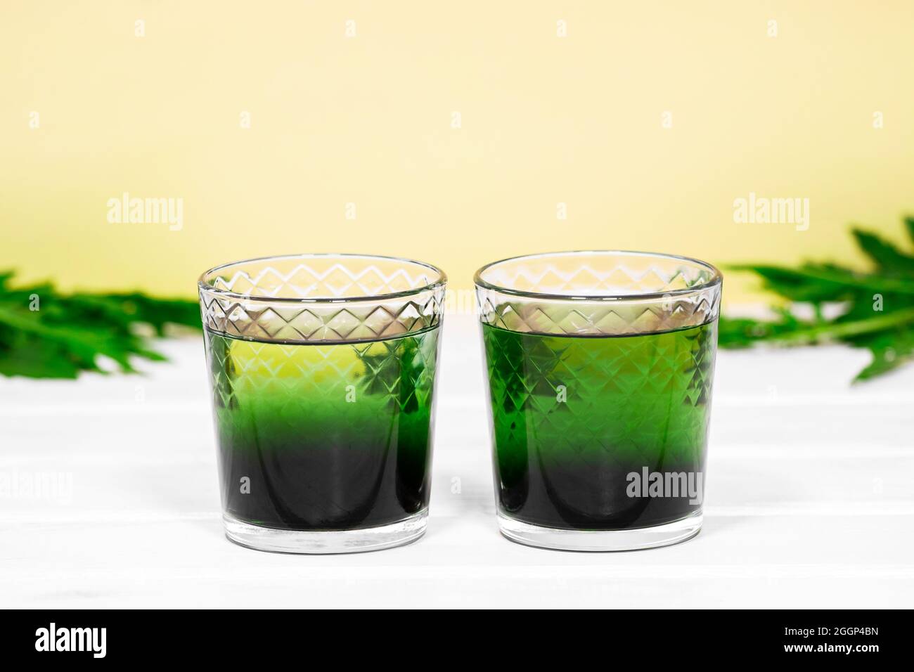 Green Chlorophyll drink in glass with water drops on white table ...