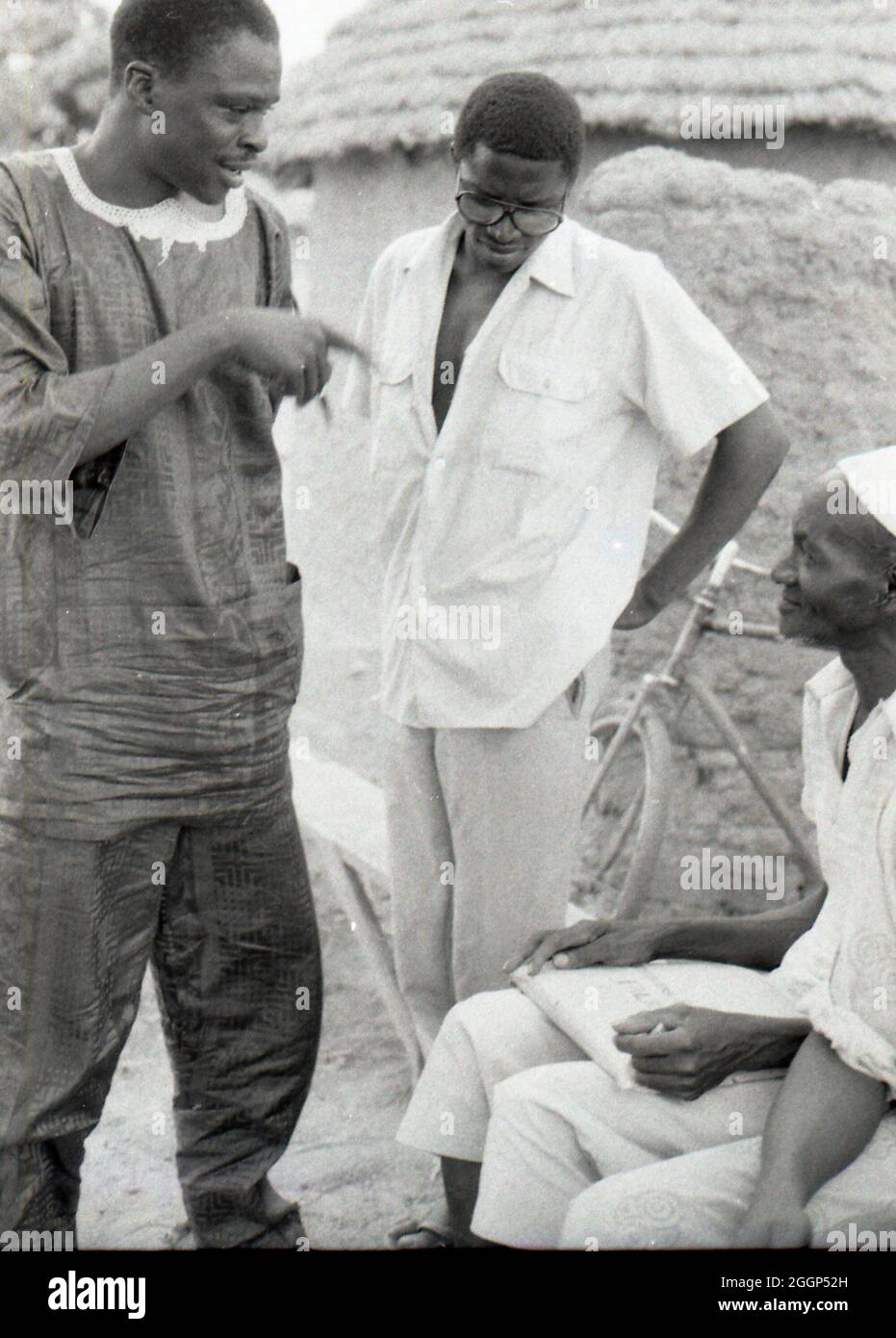 A man standing talking to another man sitting down Stock Photo - Alamy