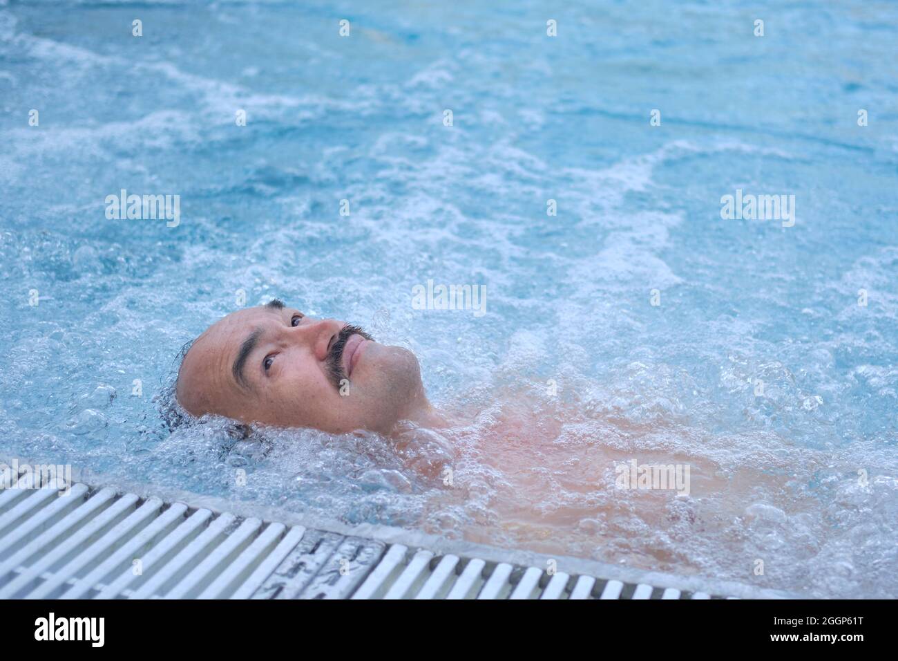 Happy mature asian man laying on water relax in outdoor thermal pool ...