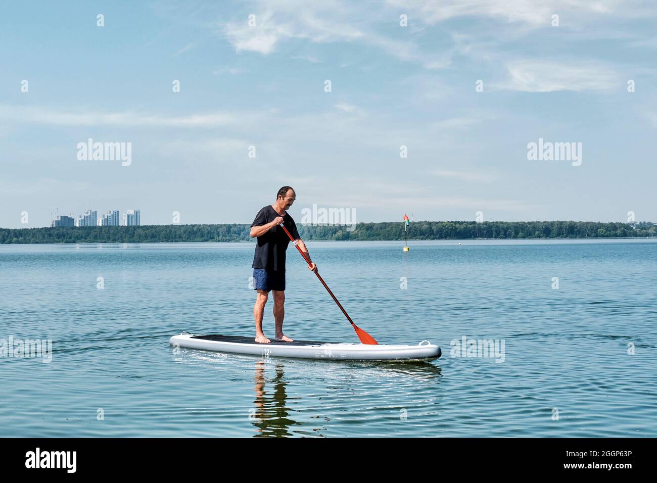 Asian older man on sup board on calm lake Stock Photo - Alamy