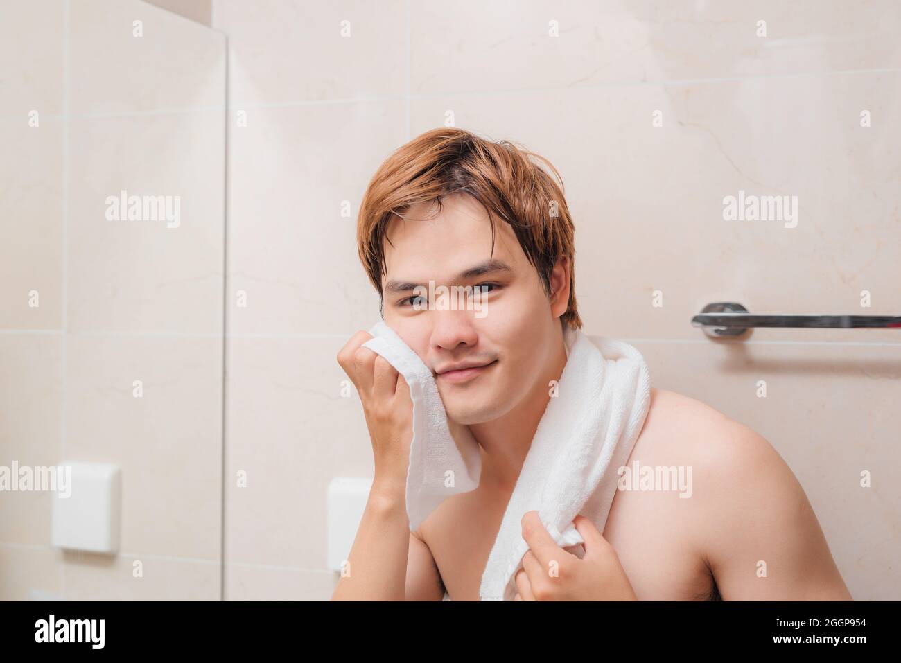 Young Man Drying Face With Towel As Part Of Daily Hygiene Routine Stock