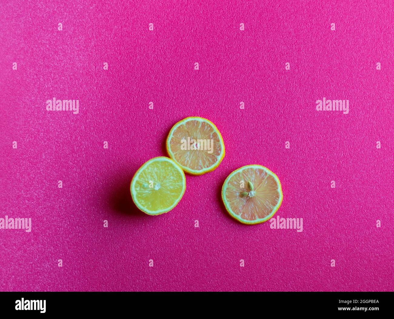 Slices of a lemon on bright pink background Stock Photo - Alamy