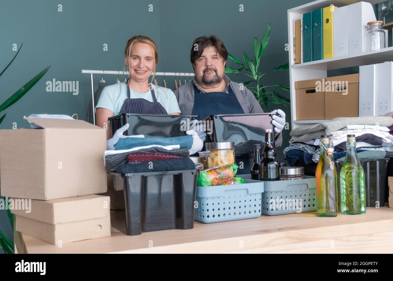 Men and Woman pack in boxes clothes and products for charity and ...
