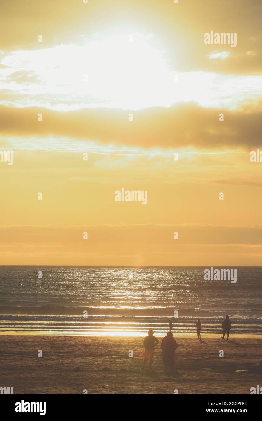 Coastal travel destination of a warm beach at sunset with people ...