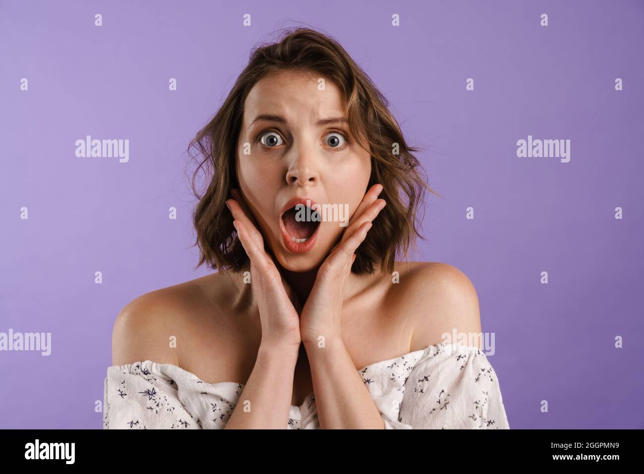 Shocked young woman screaming while expressing surprise isolated over ...