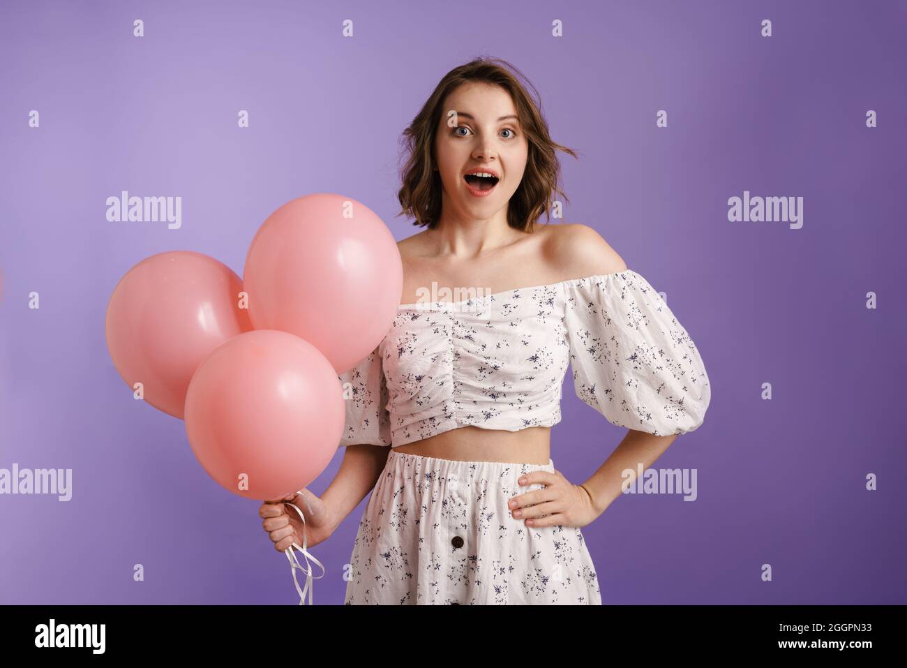 Excited young woman exclaiming while posing with balloons isolated over ...