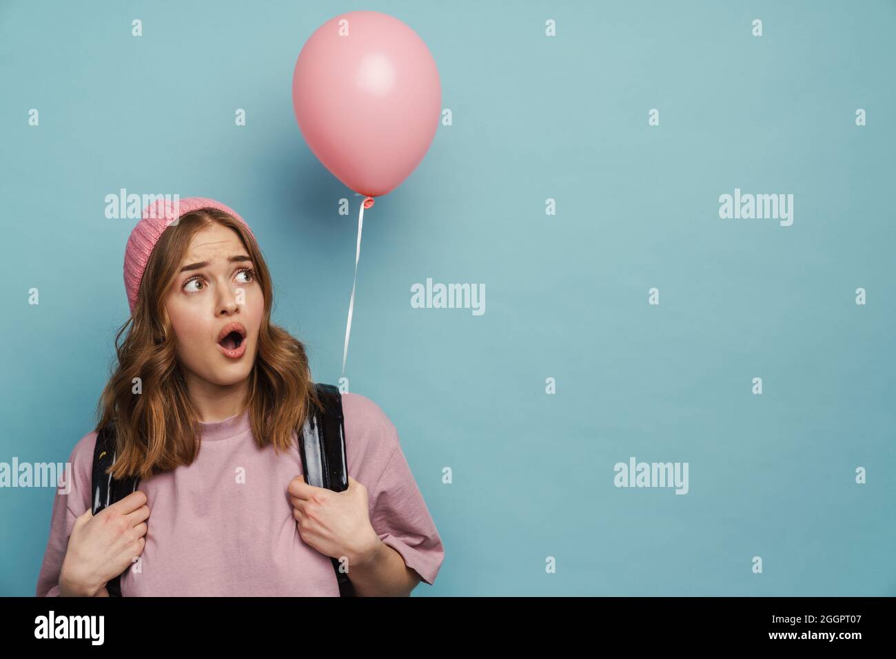Young scared student girl expressing surprise while posing with balloon ...
