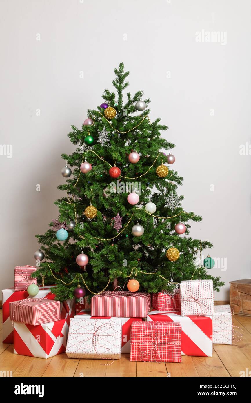 Wrapped boxes with gifts under a Christmas tree in a light room Stock ...