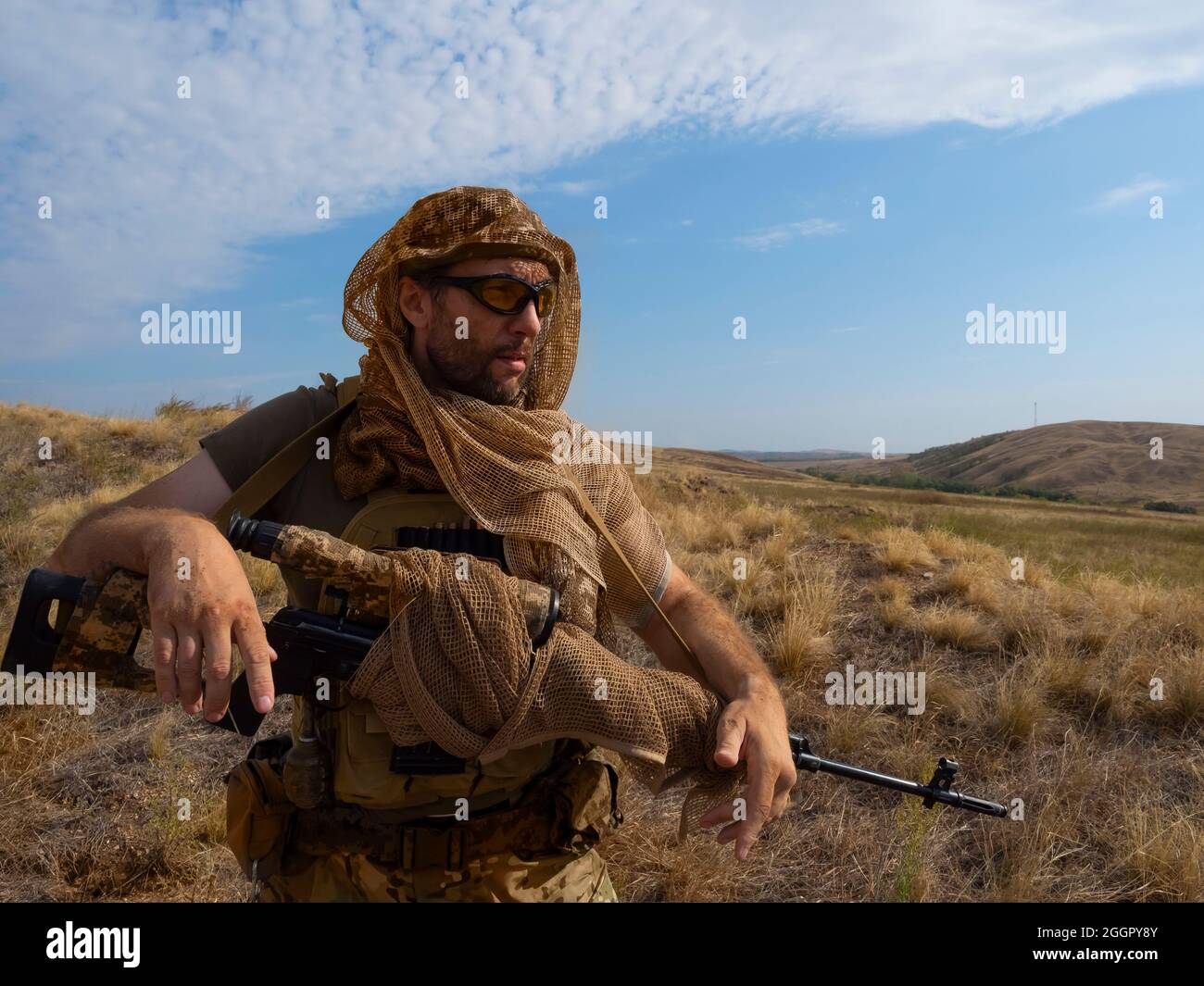 A mercenary sniper in camouflage clothes under the scorching sun. He ...