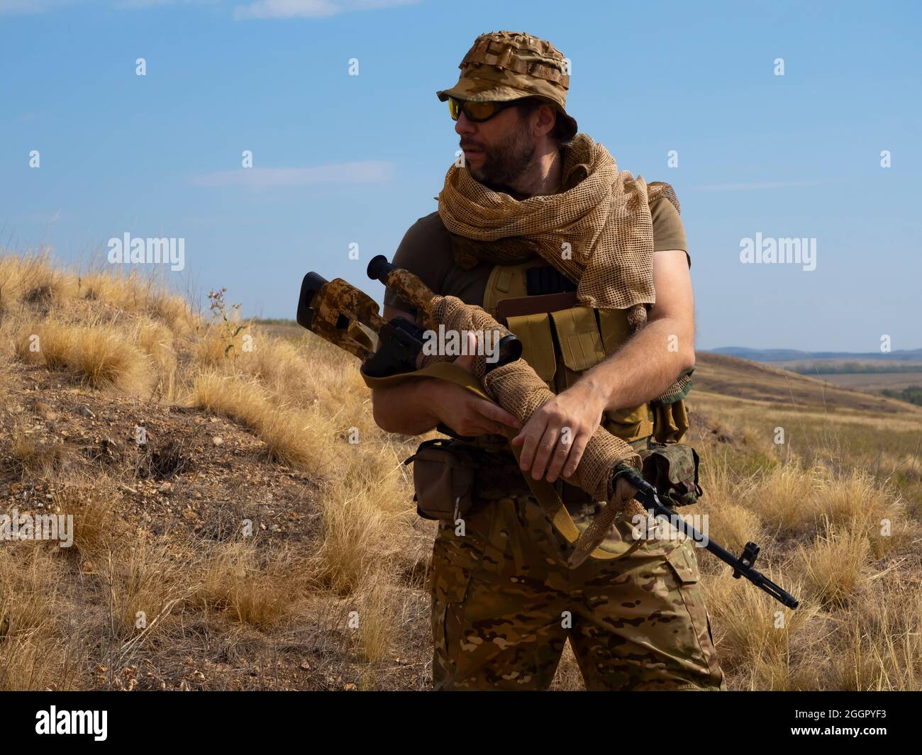 Mercenary sniper in camouflage clothes under the scorching sun. He ...