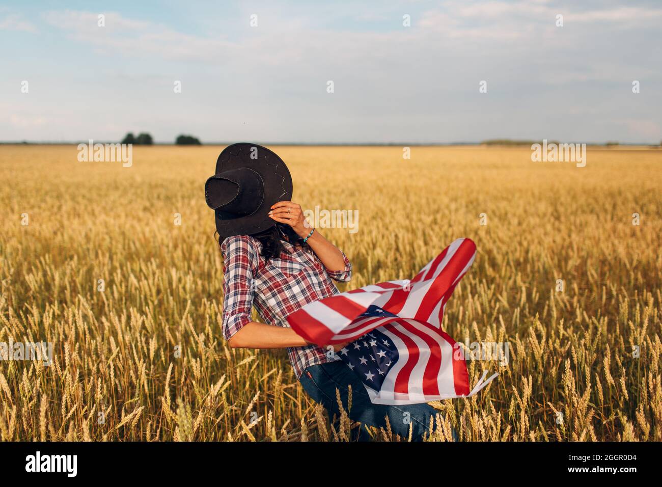 Woman farmer wearing cowboy hat, plaid shirt and jeans with american ...