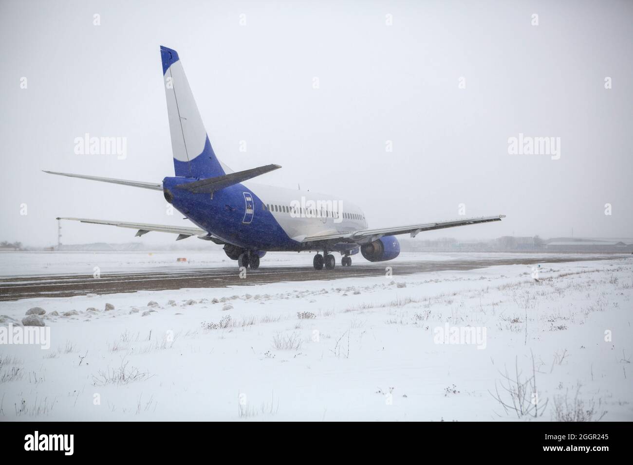 Airliner on runway in blizzard. Aircraft during taxiing on landing ...