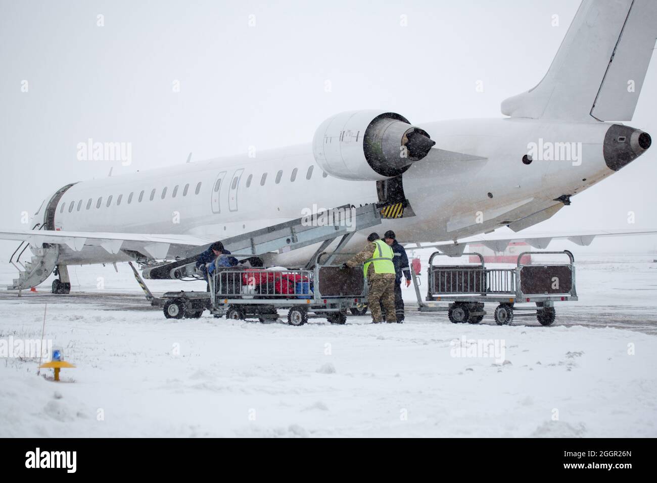 baggage loading at airport in winter. Luggage in carts near aircraft in ...