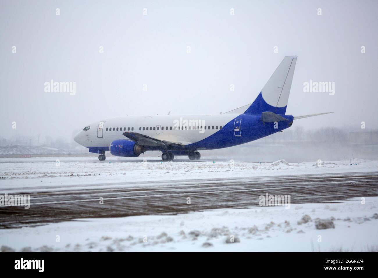 Airliner on runway in blizzard. Aircraft during taxiing on landing ...