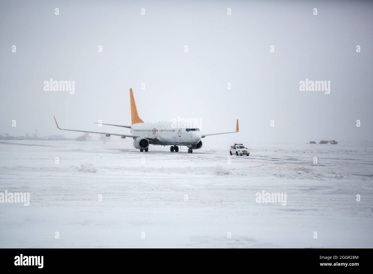 Airliner on runway in blizzard. Aircraft during taxiing on landing ...