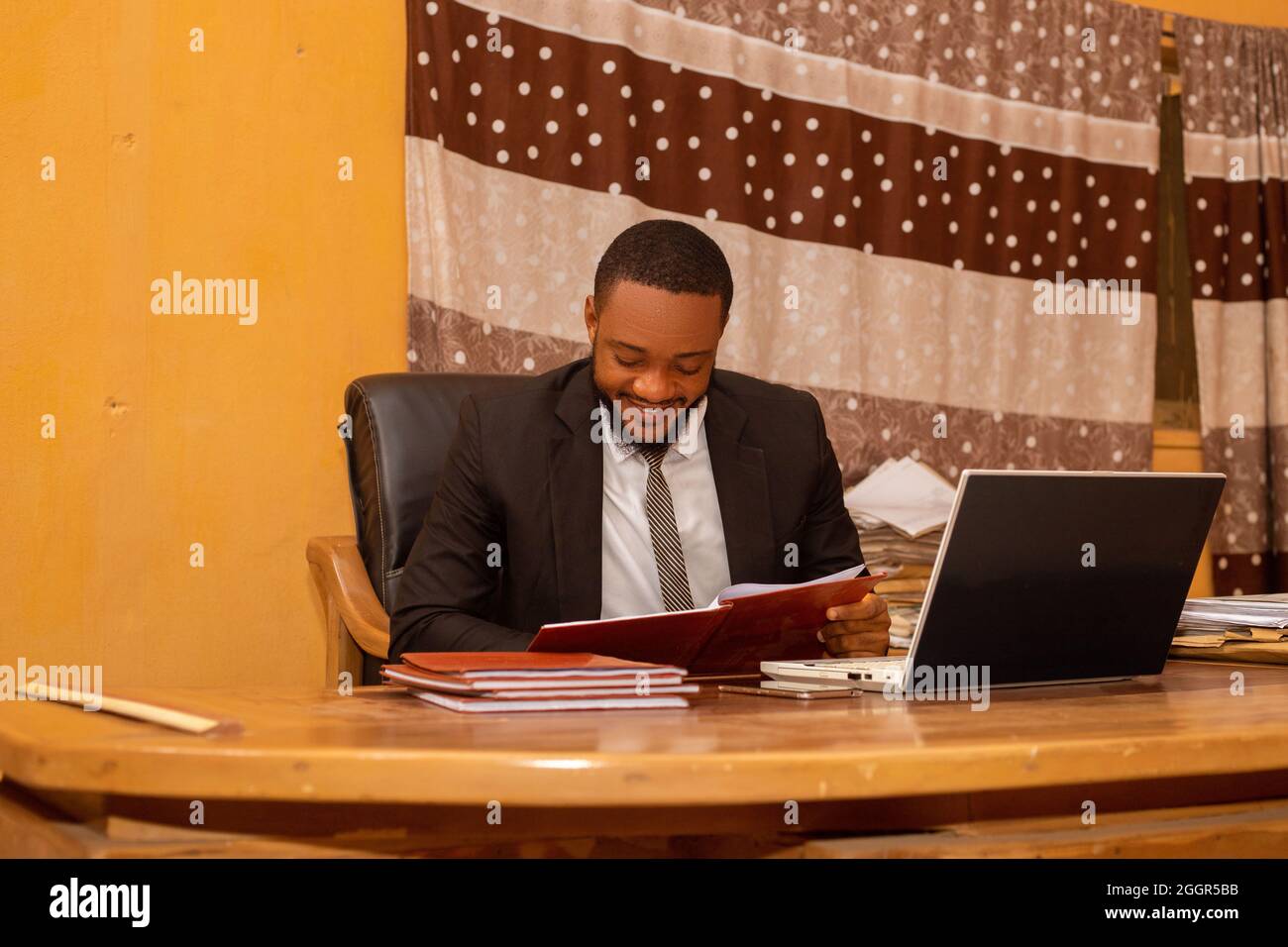 Smiling African businessman reading files by his desk Stock Photo - Alamy