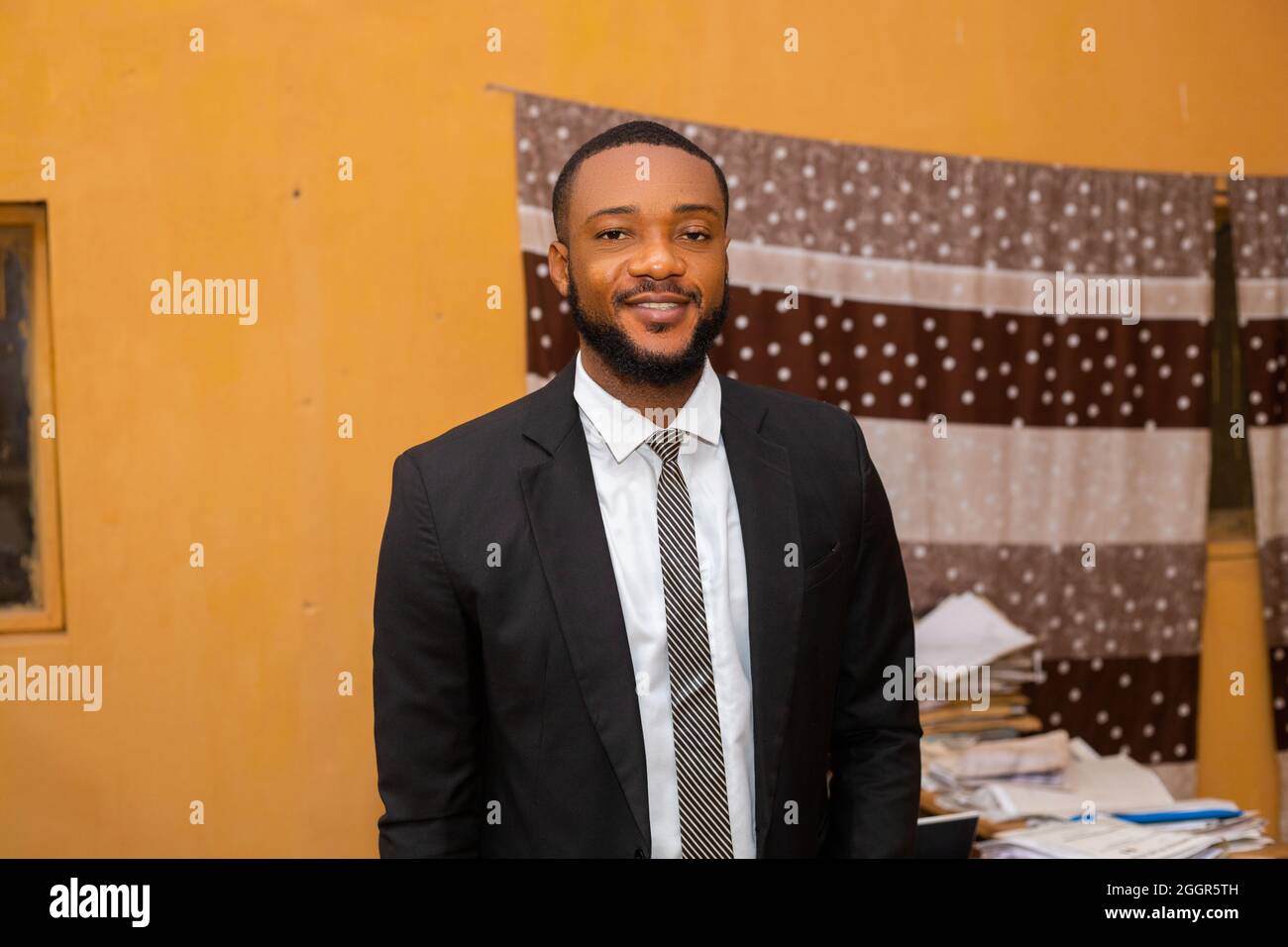 Smiling African man in a black suit in his office Stock Photo - Alamy