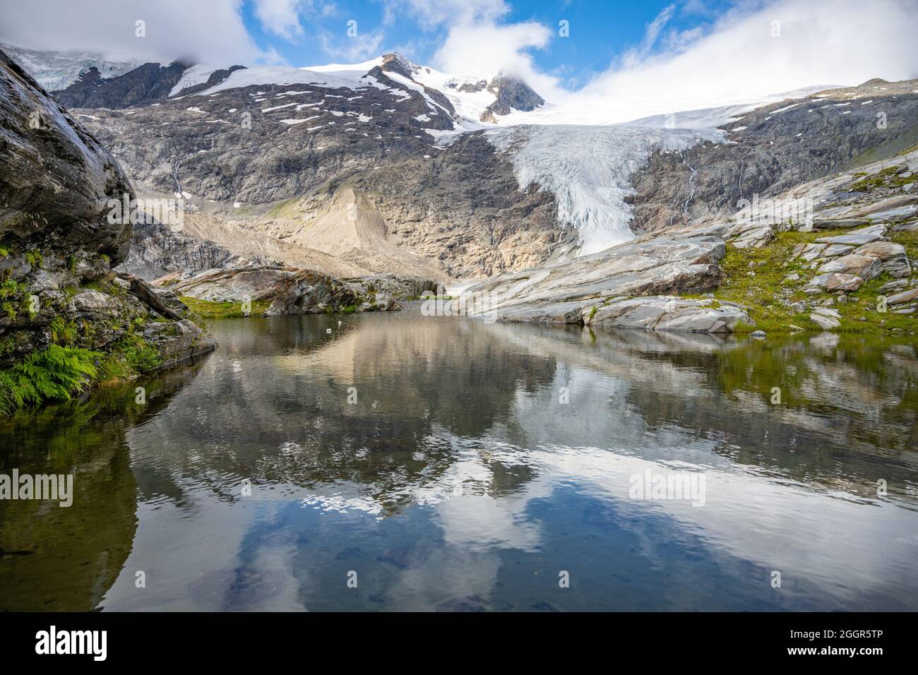 Mountain Glacier in alpine valley reflected in water. Schlaten Glacier ...