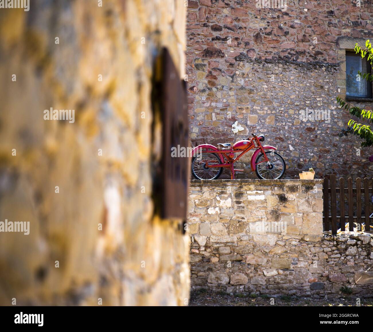 Shot of a vintage red motorcycle standing on a stone platform near a ...