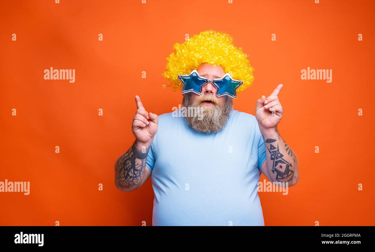 Fat thoughtful man with beard, tattoos and sunglasses dances music on a ...