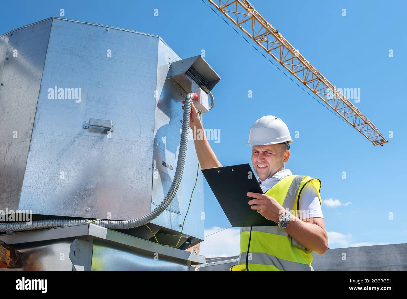 Engineer with clipboard checking the installation of the ventilation ...