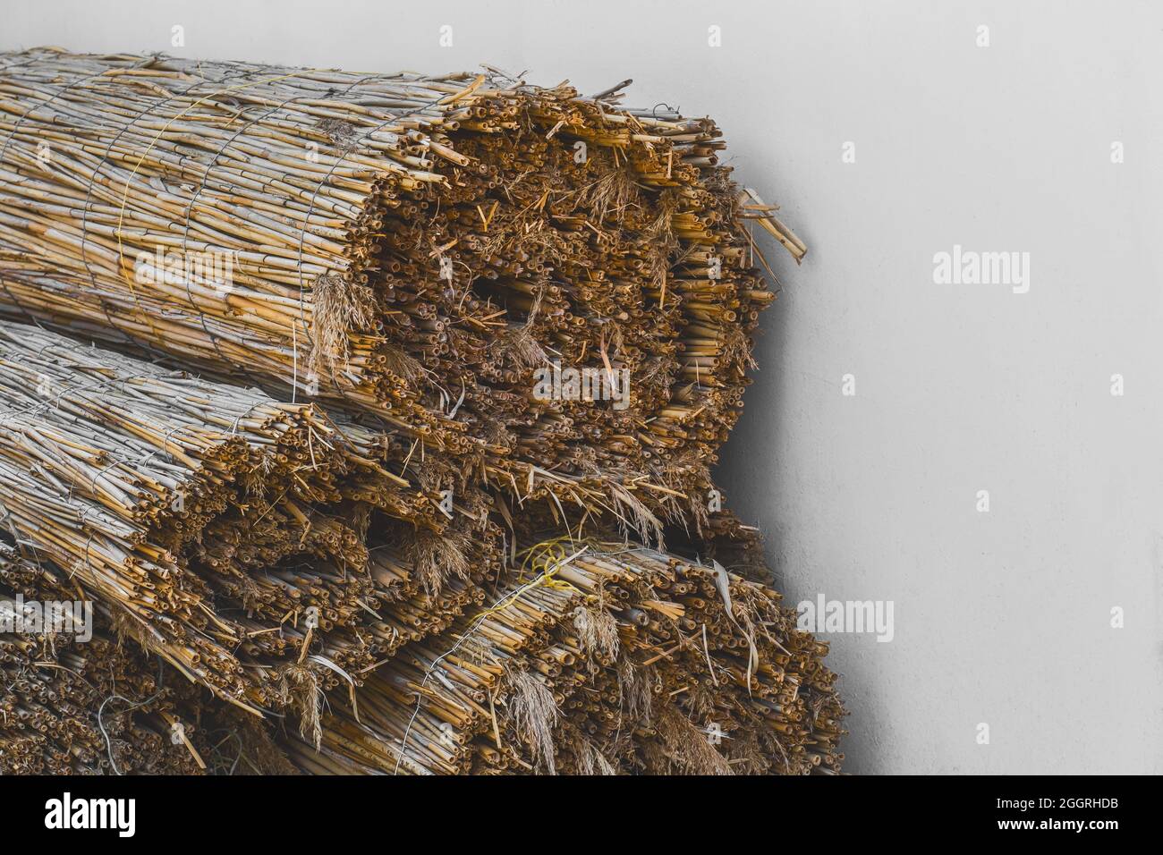 Straw rope dry reed natural material is stored in rolls on a white ...