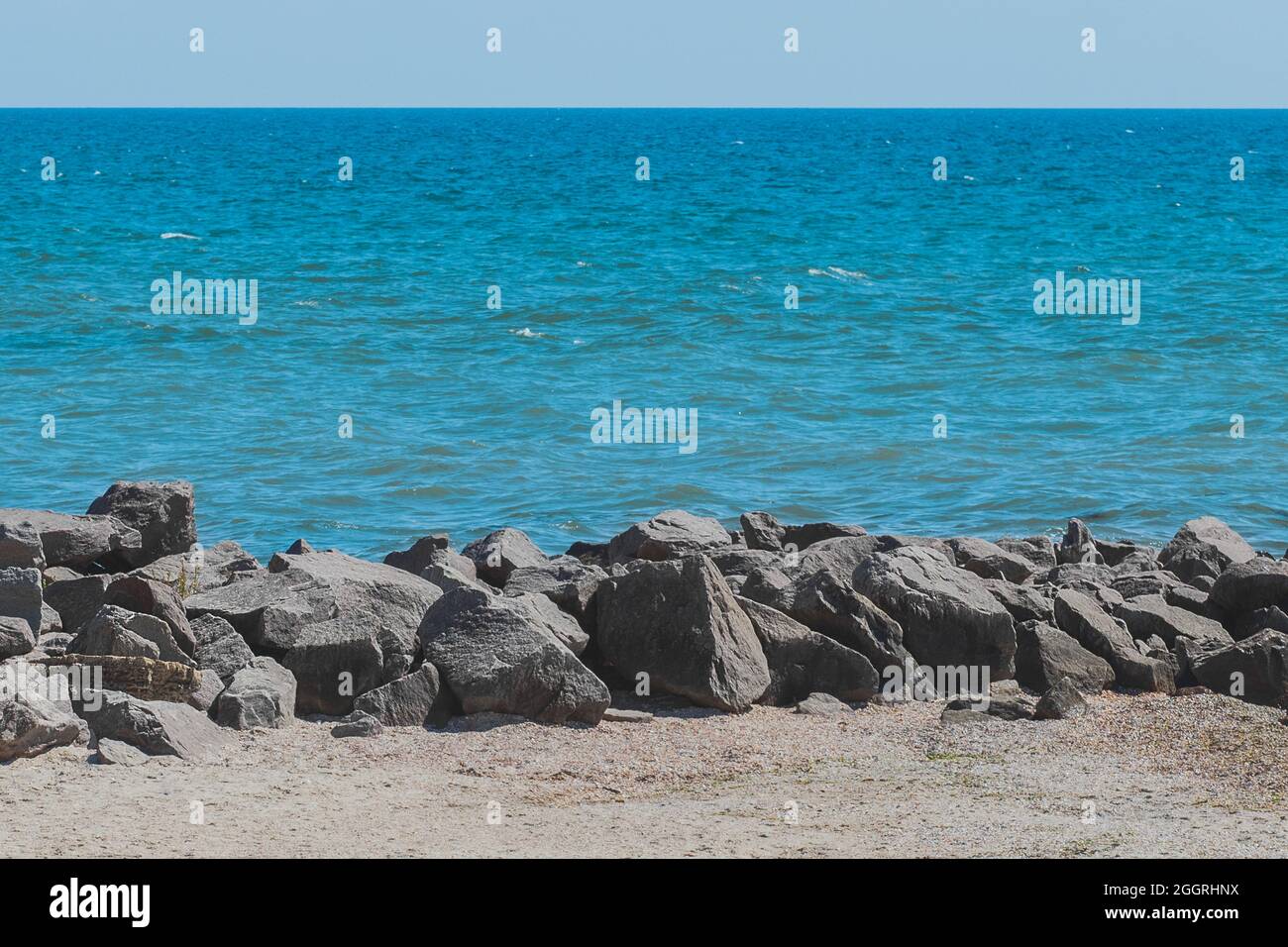 Breakwater beach stones on the sea coast with blue water against the ...