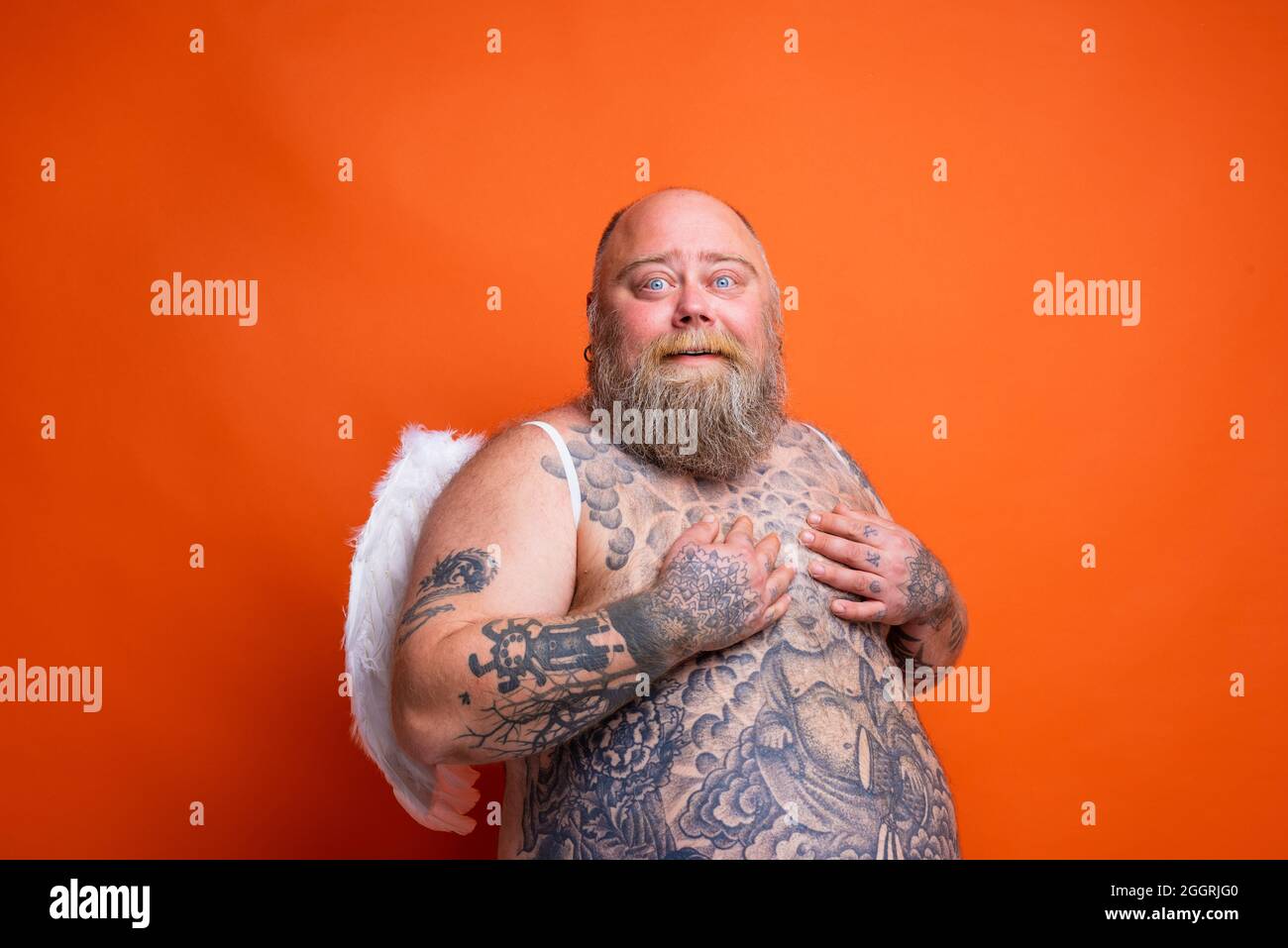 Fat amazed man with beard ,tattoos and wings acts like an angel Stock ...