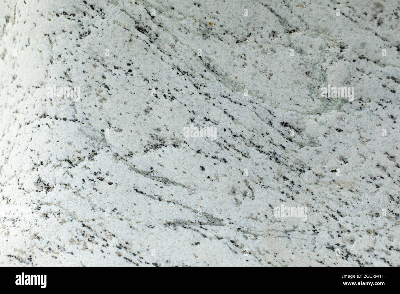 The texture of white stone with inclusions of black dots and lines. The ...