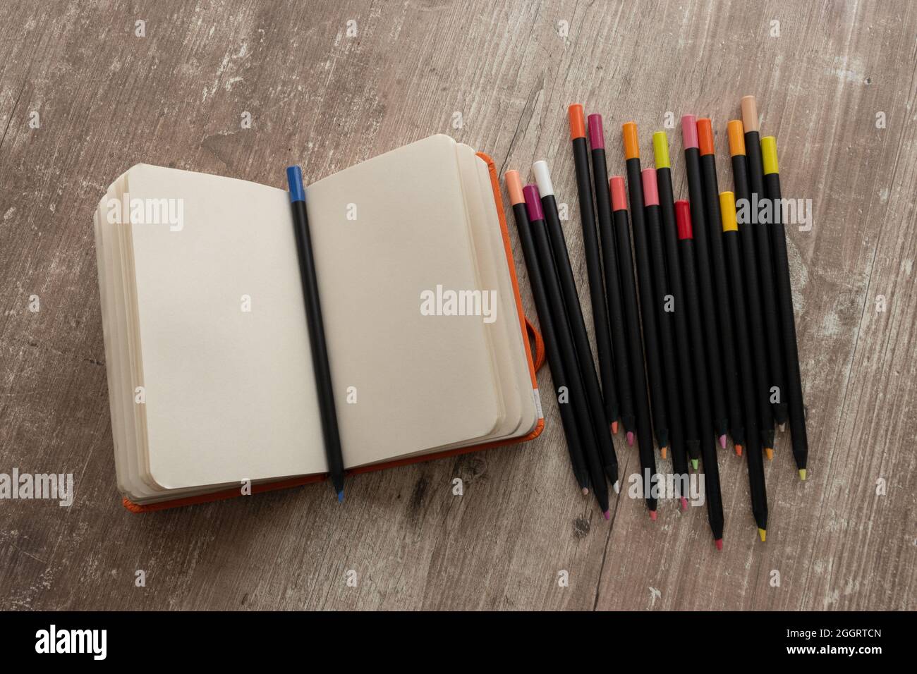 detail of notebook with blank sheets and colored pencils, on a wooden ...