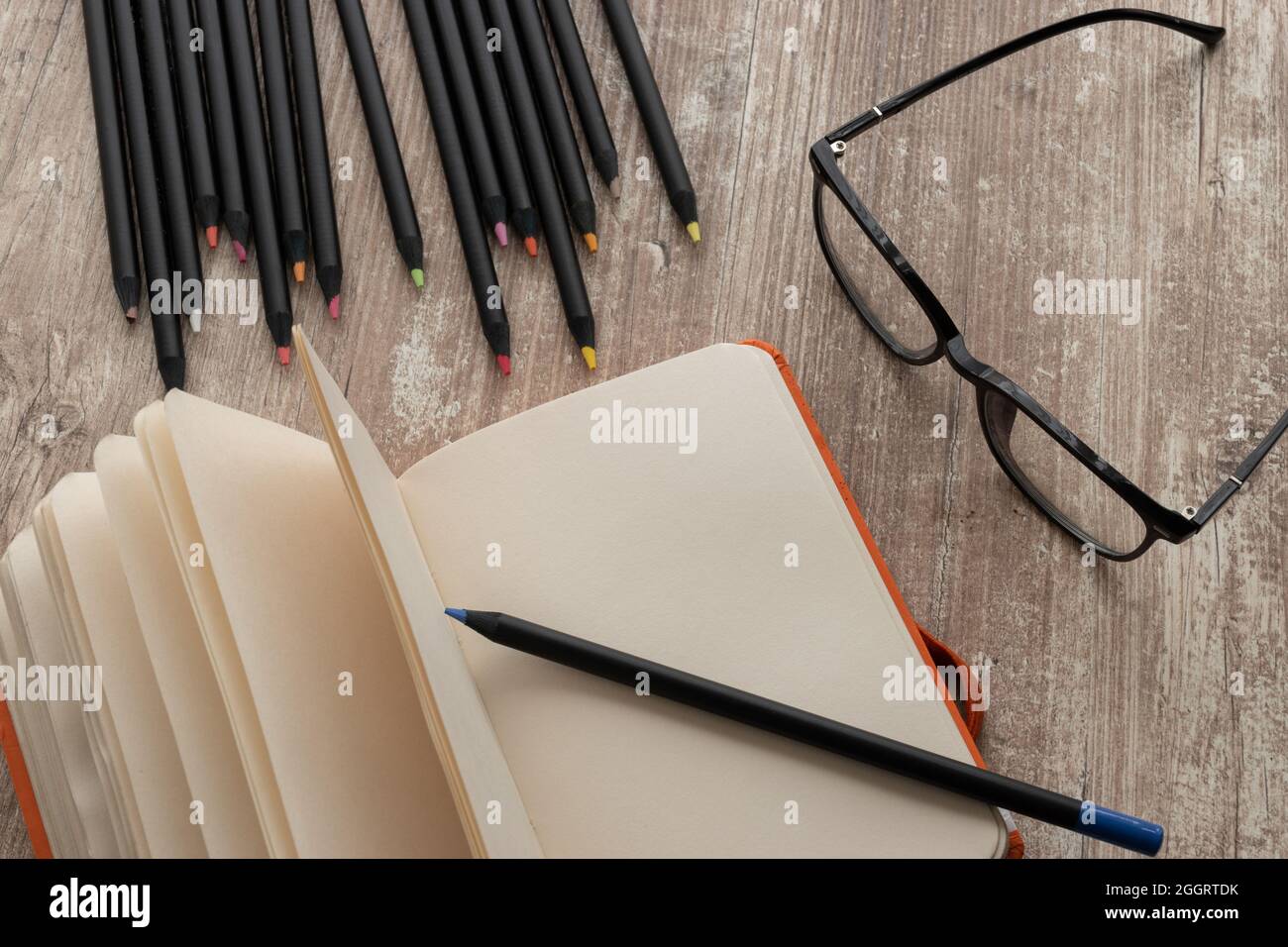 open notebook with colored pencils and glasses on a wooden textured ...