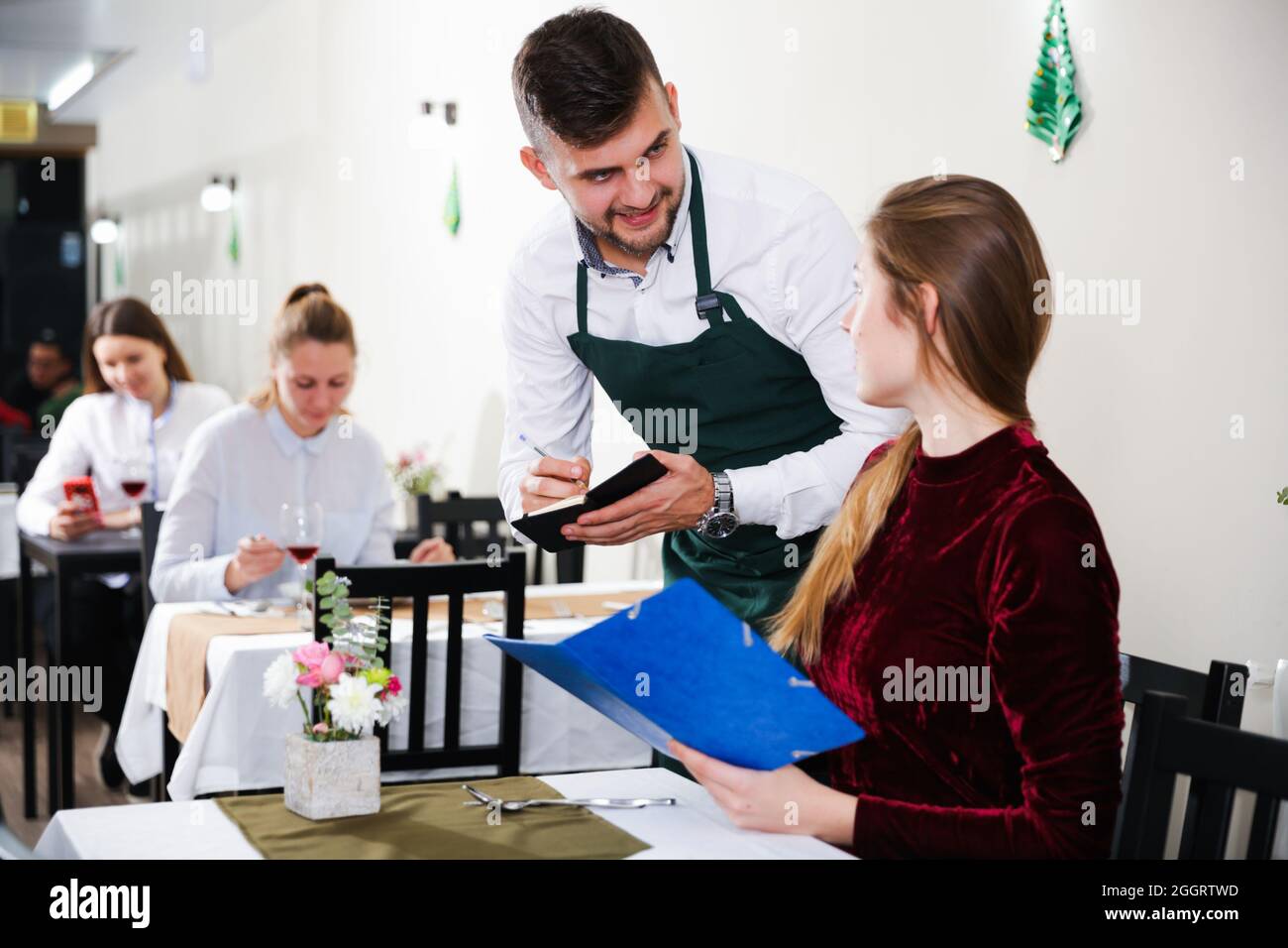 Waiter is taking order from young female in restaurante Stock Photo - Alamy