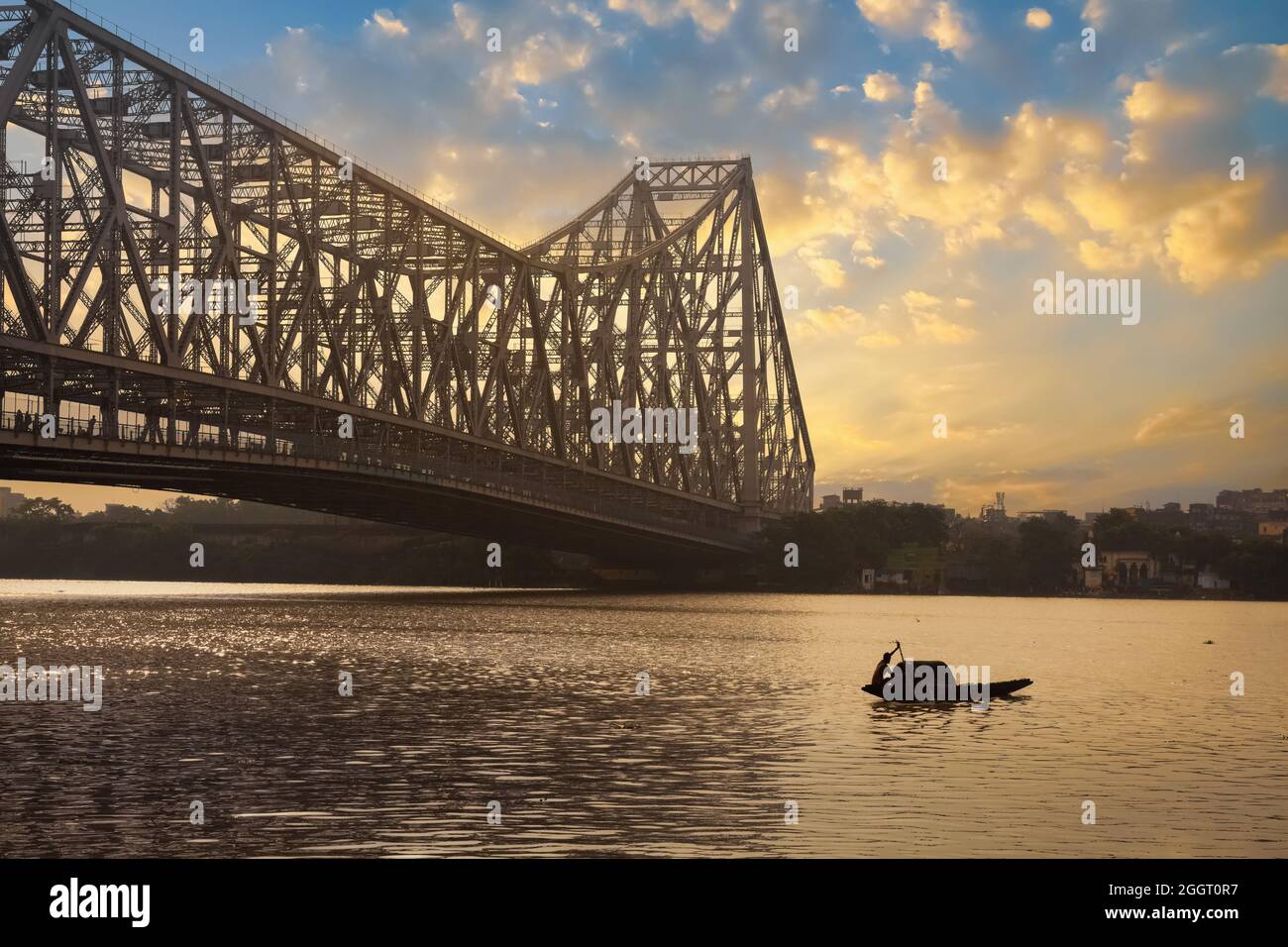 Howrah bridge at sunset with view of a fishing boat on river Ganges and ...