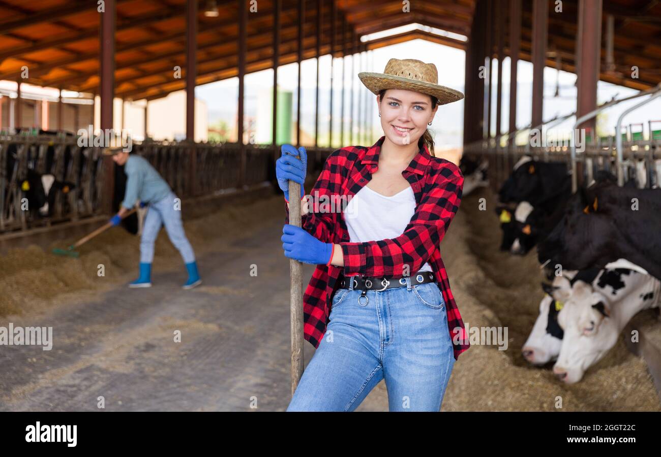 Smiling young woman cow breeder standing in cowshed Stock Photo - Alamy
