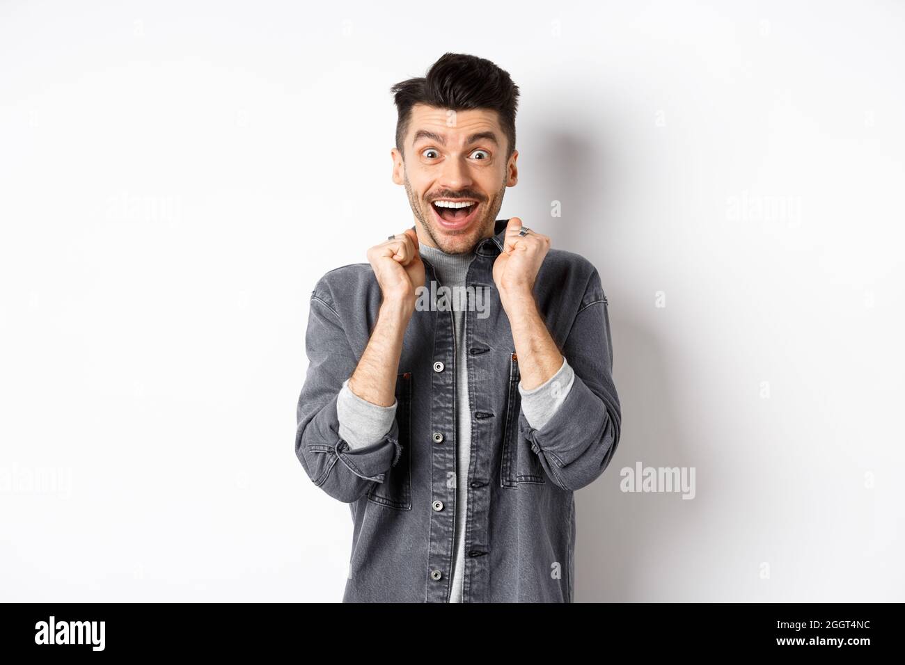 Excited young man jumping from happiness, smiling amazed and holding ...