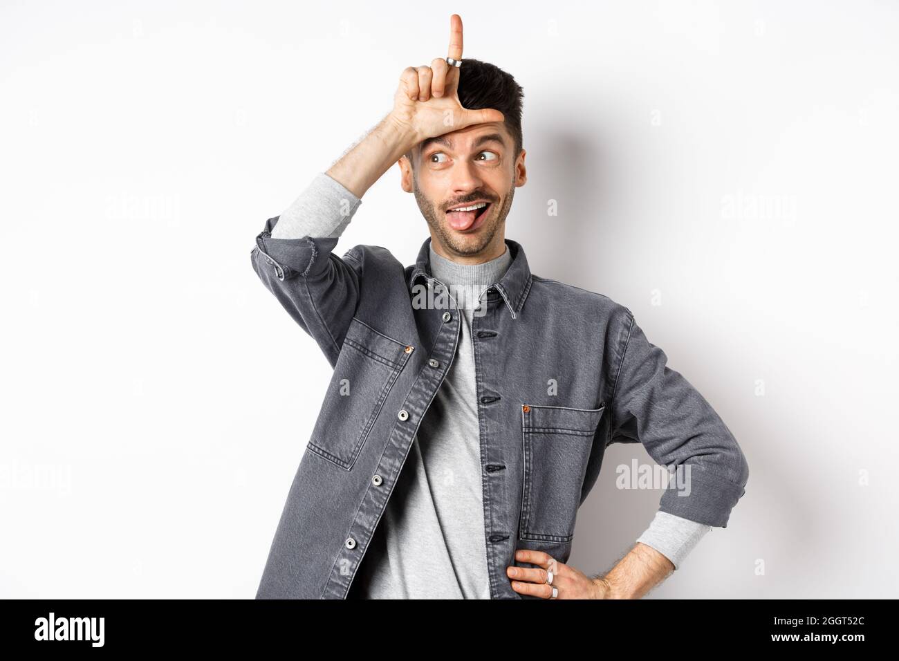 Funny guy mocking person, showing tongue and loser sign on forehead ...