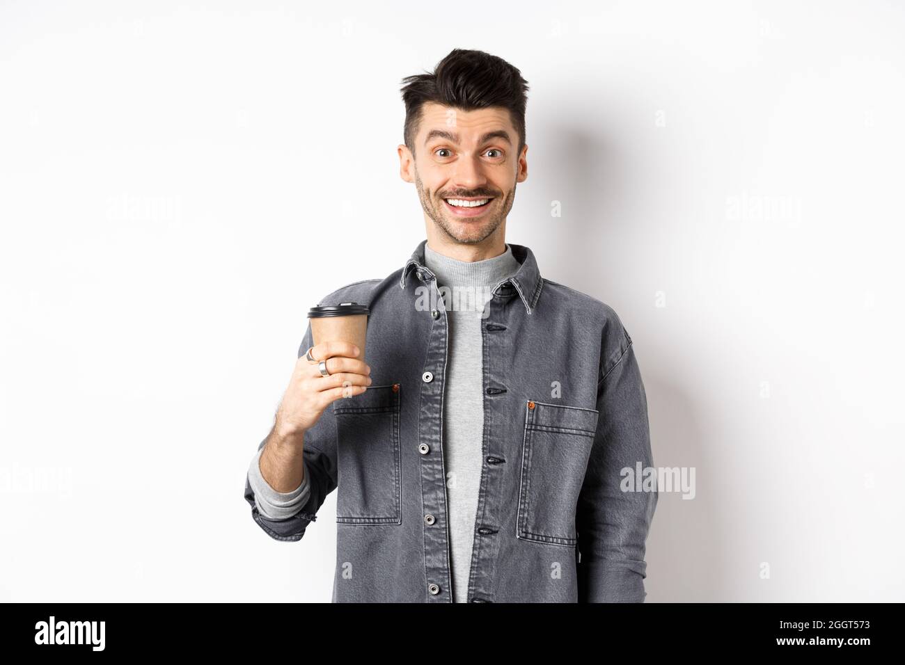 Enthusiastic handsome man holding coffee cup and smiling, drinking good ...